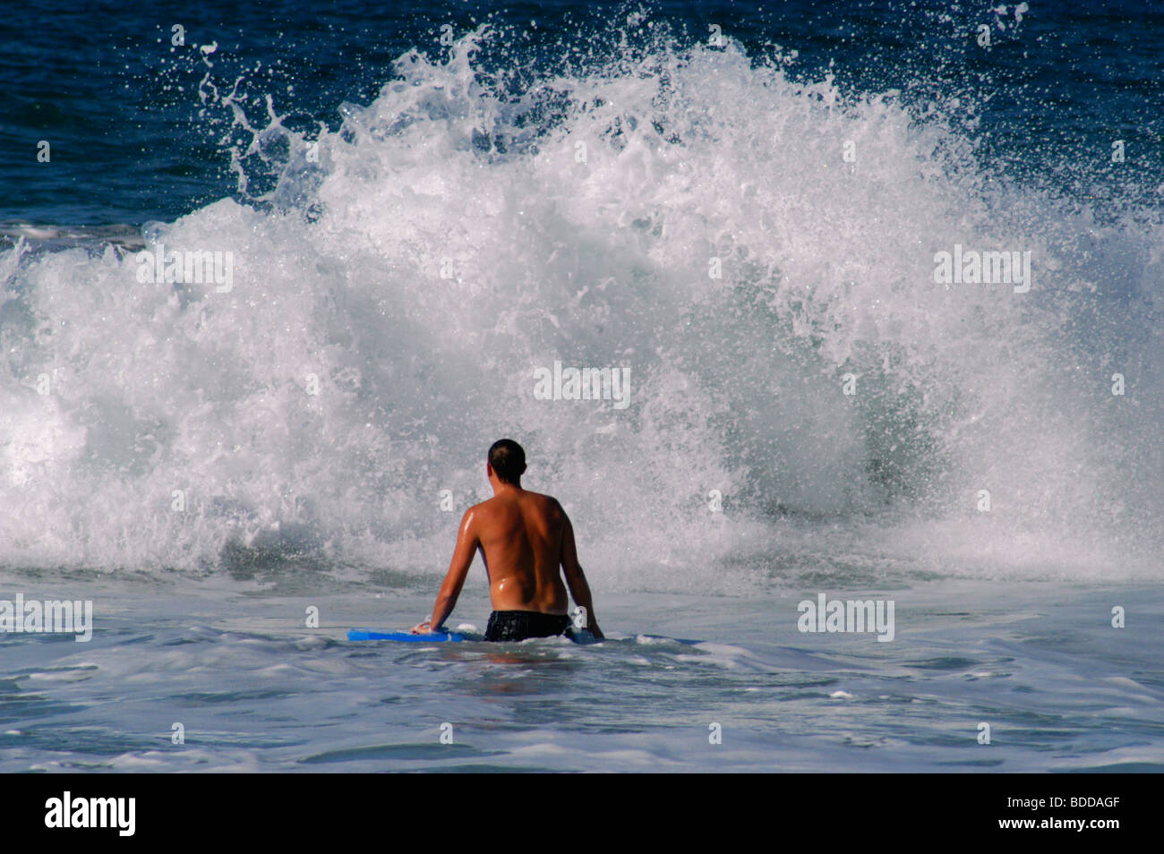 A surfer floats his body board (boogie board) as he heads toward a ...