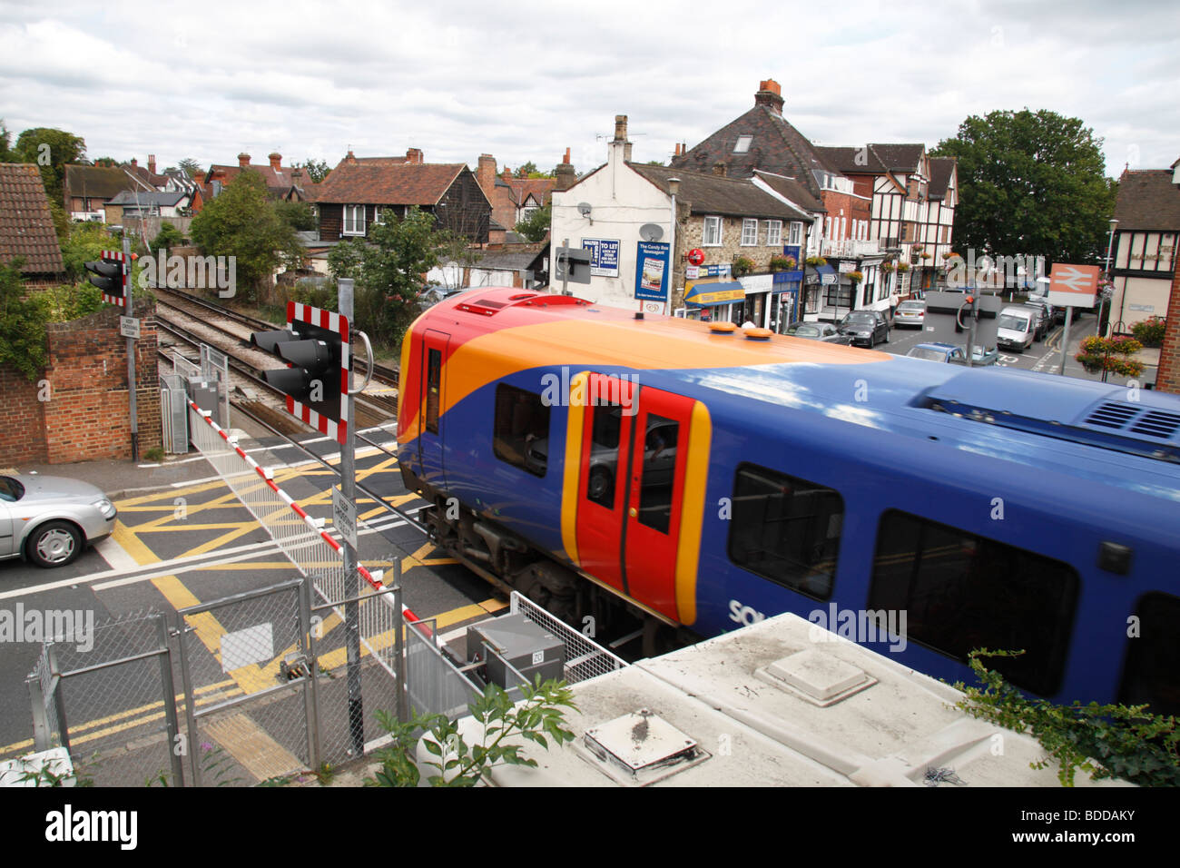 Cars wait as a South West Trains commuter train passes a railway level ...