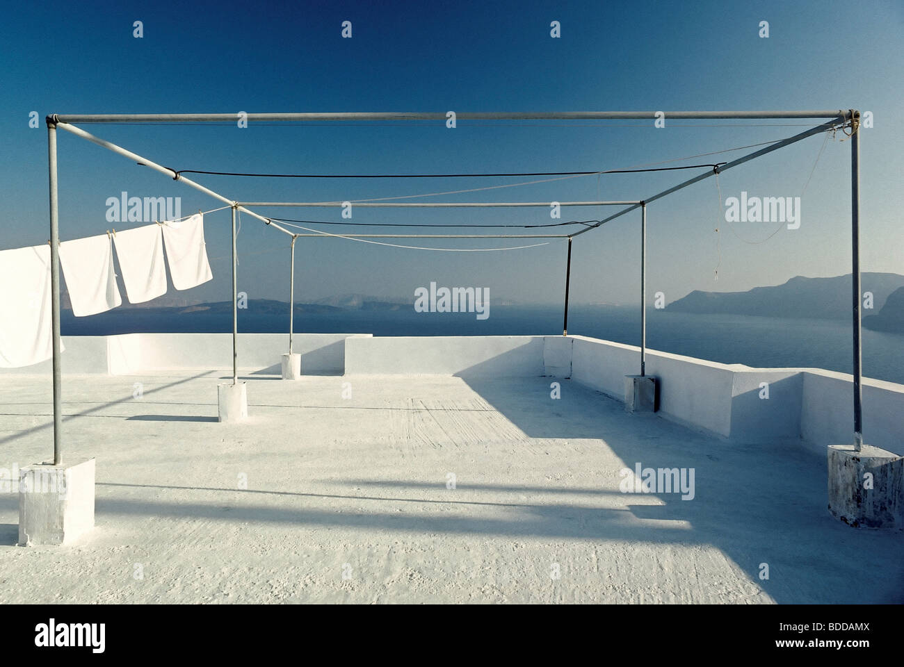 White roof-deck of a Cycladic house, white laundry hung out to dry ...