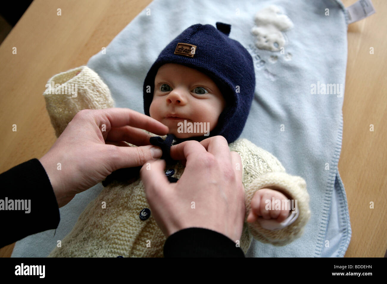 A one month old child getting wrapped up warm by mum ready to go ...