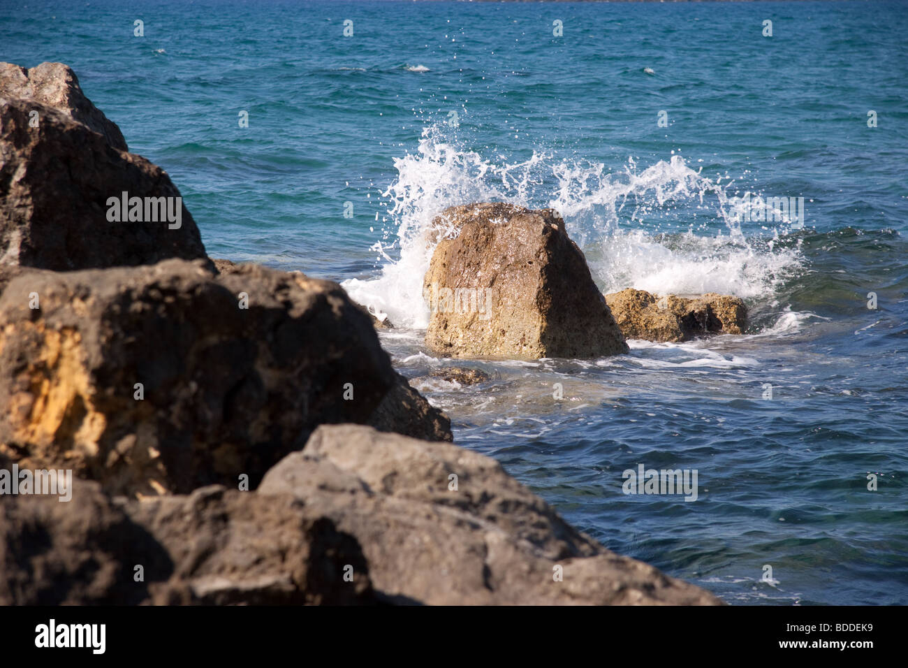 A wave breaks over a rock Stock Photo - Alamy