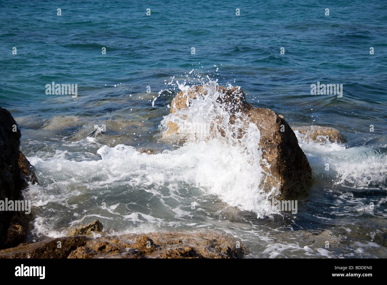 A wave breaks over a rock Stock Photo - Alamy