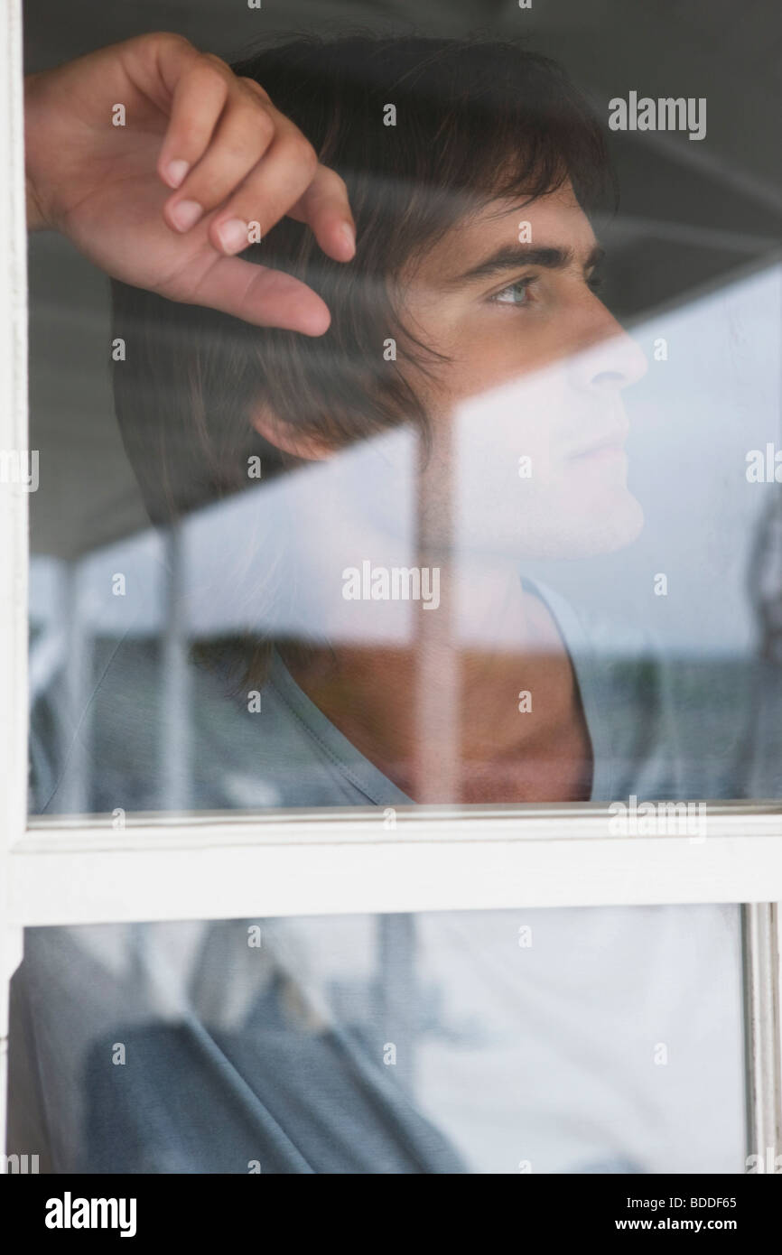Man looking through glass window Stock Photo - Alamy