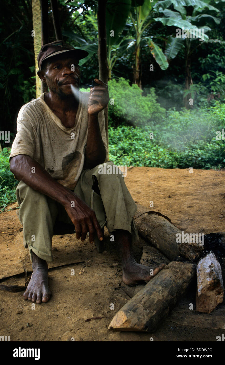 A Baka Pygmy man smoking in his remote village in the rainforest ...
