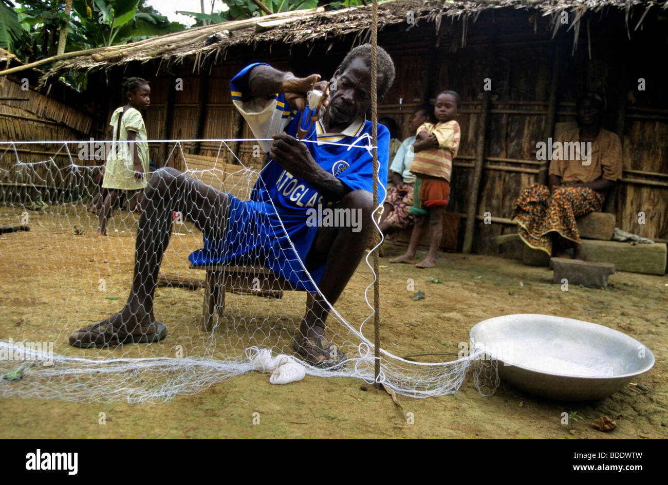 Pygmy man repairing fishing net in his remote village in Gabon, Central ...