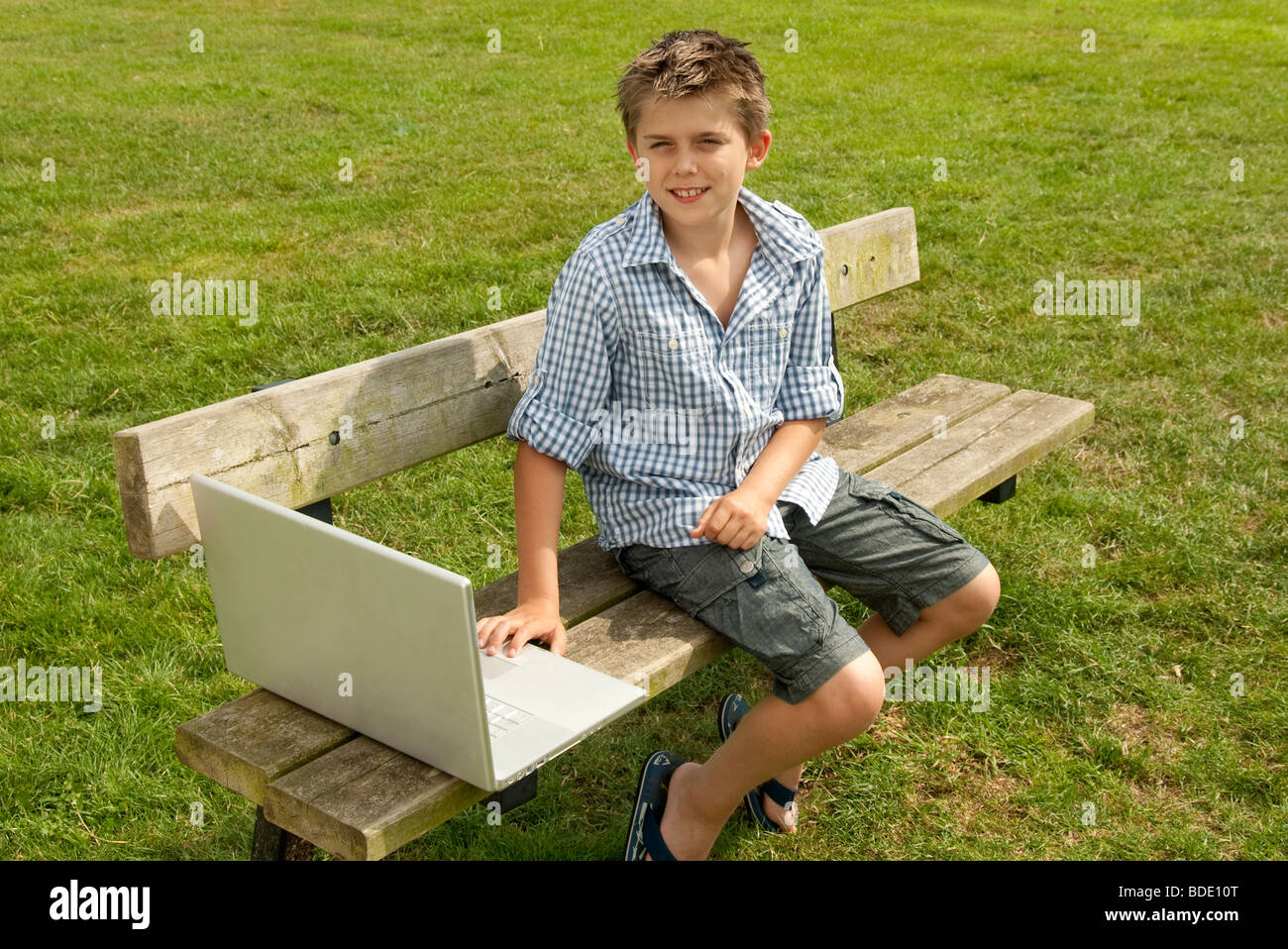 boy sitting on bench using laptop Stock Photo - Alamy