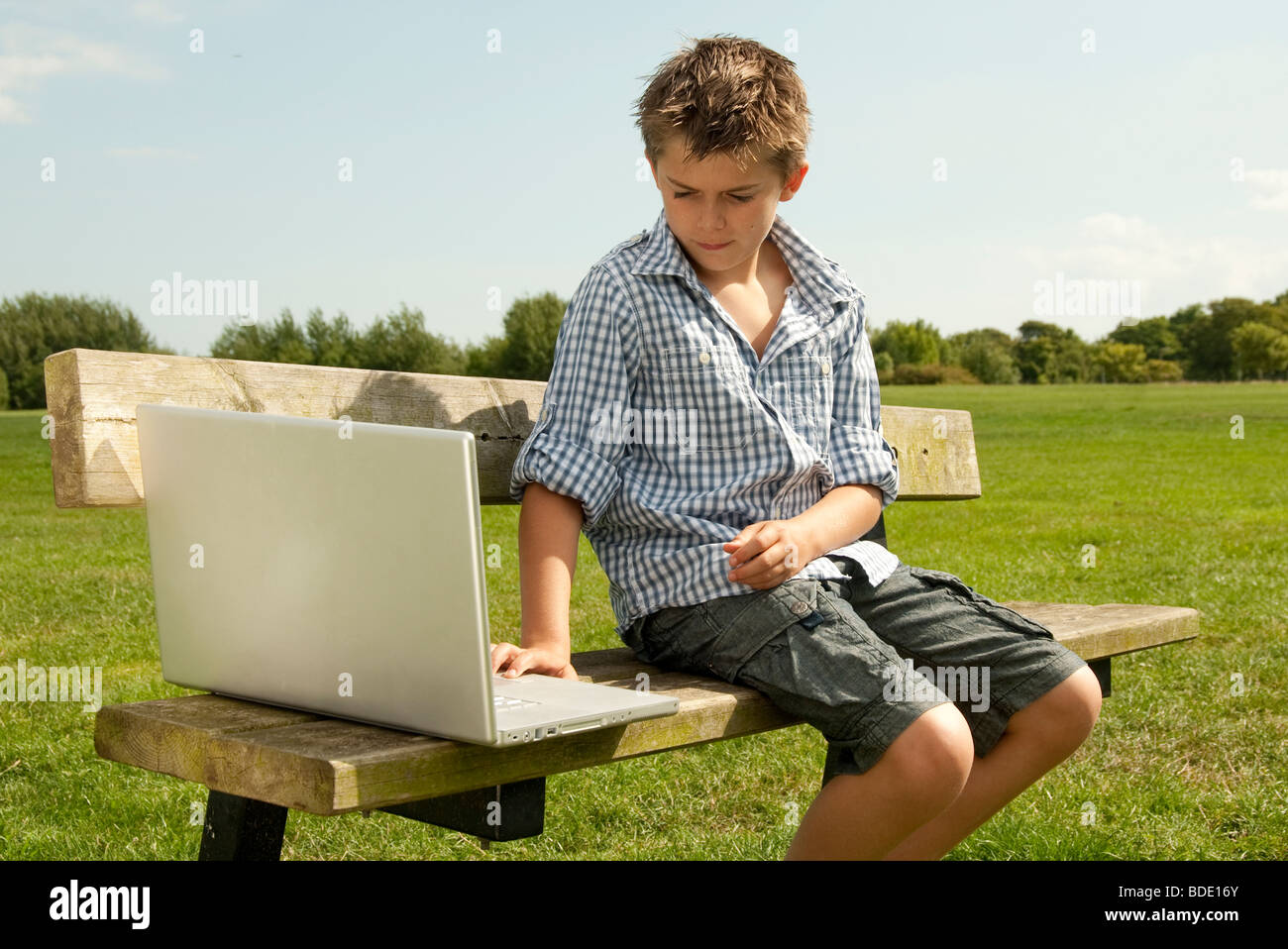 boy sitting on bench using laptop Stock Photo - Alamy