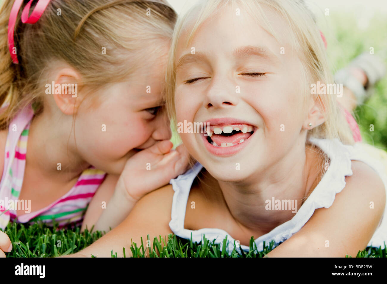 Two smiling girls sharing secrets hi-res stock photography and images ...