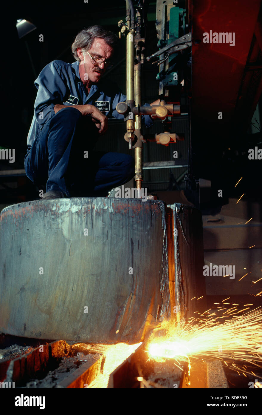Worker operating an automated cutting machine at a metal production ...