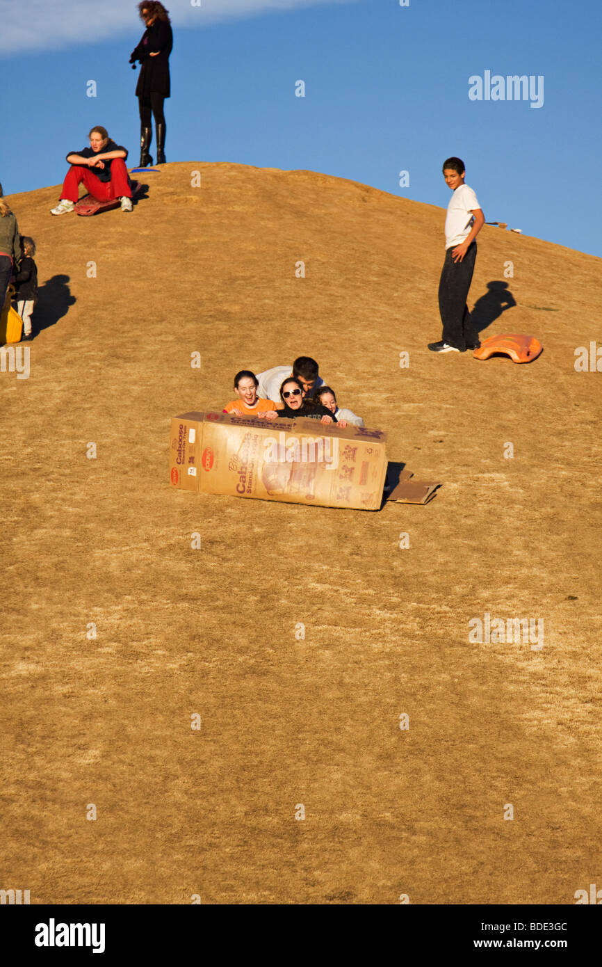 People sliding down a hill on cardboard boxes Stock Photo - Alamy
