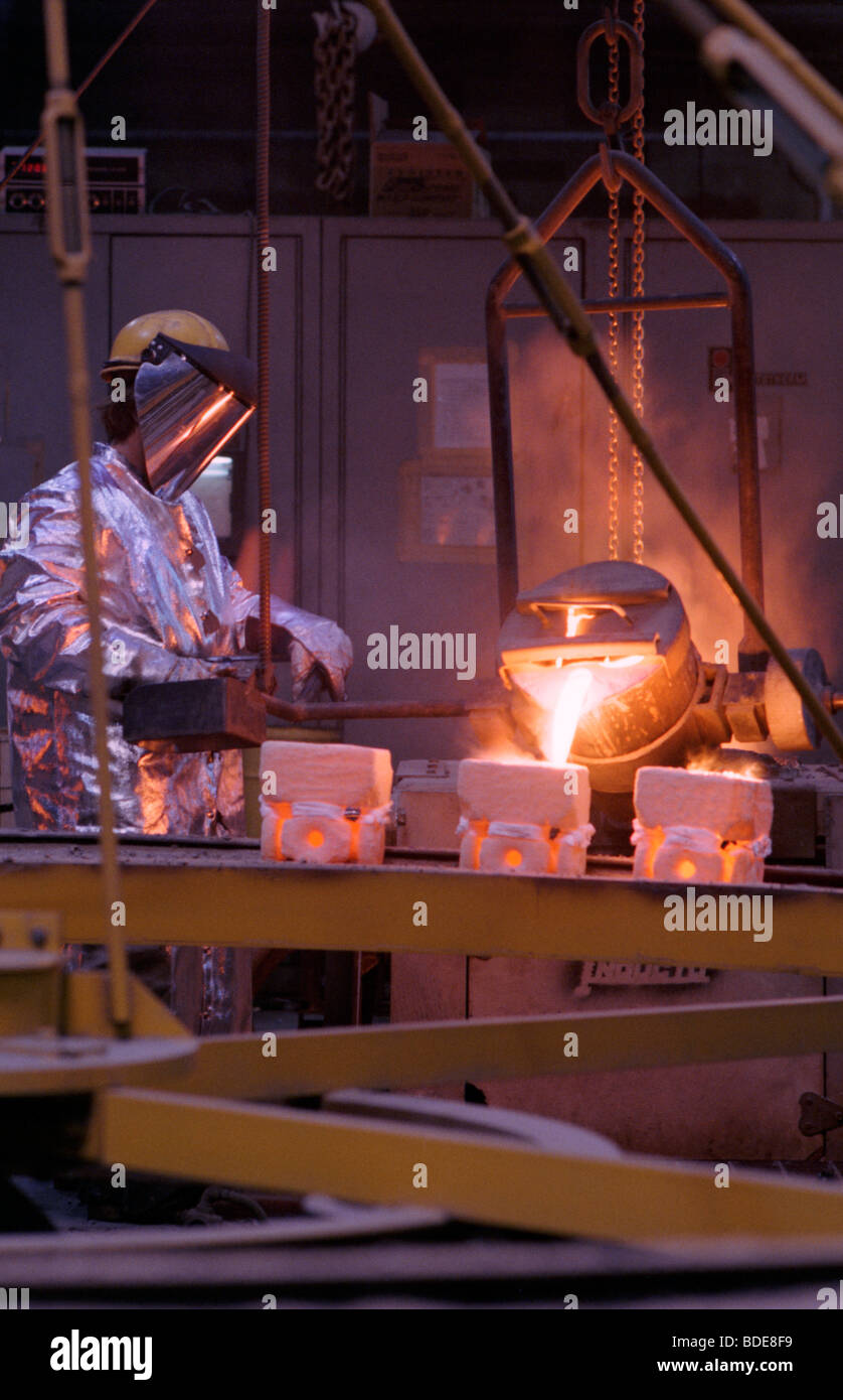 A worker pours molten steel into red hot ingot molds at a foundry in ...