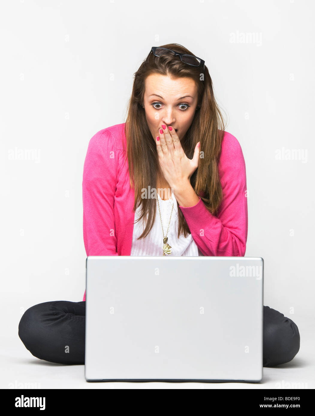 Attractive young woman shocked when working on her laptop computer ...