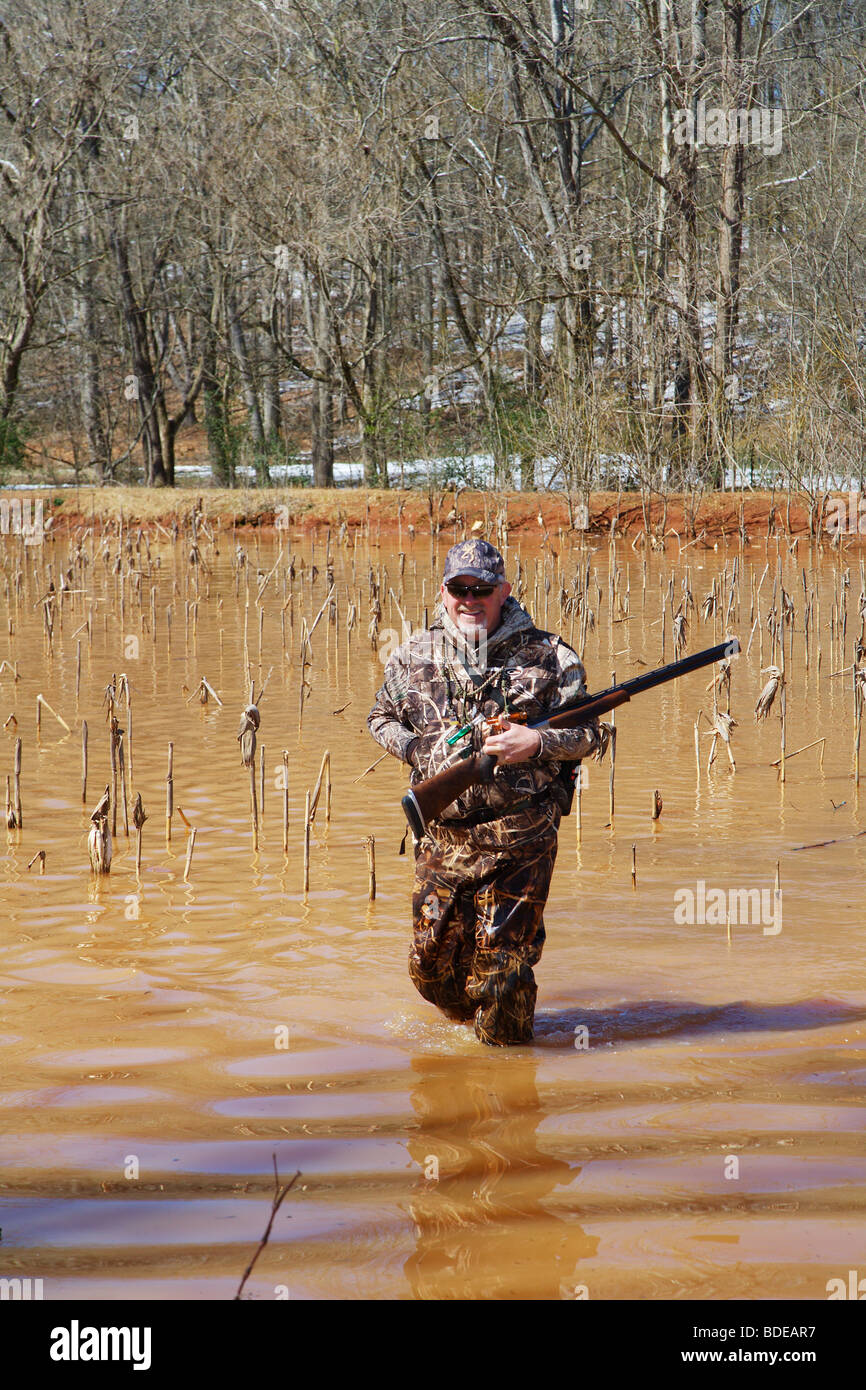 DUCK HUNTER IN CAMO WALKING IN SLOUGH HOLDING GUN Stock Photo - Alamy