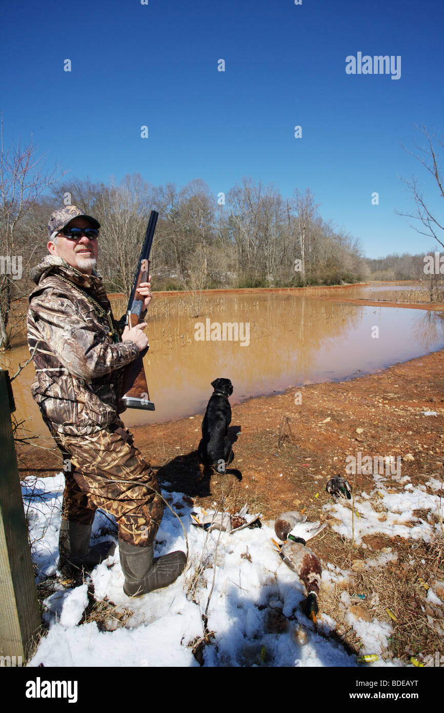 DUCK HUNTER IN CAMO LOOKING BACK FOR ONCOMING DUCKS MUDDY SLOUGH AND ...