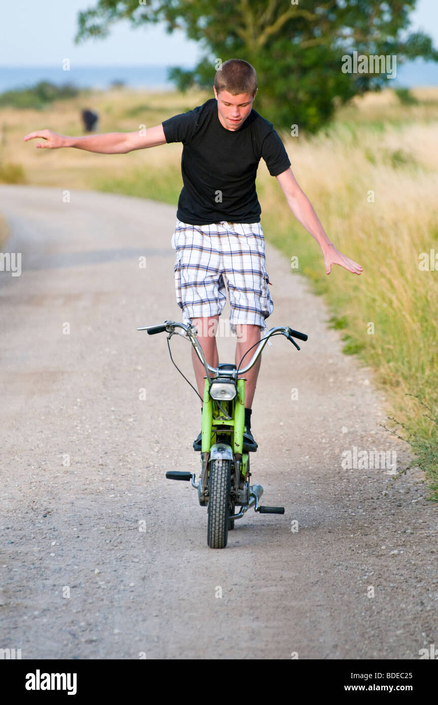 Boy standing upright balancing while driving a moped Stock Photo - Alamy