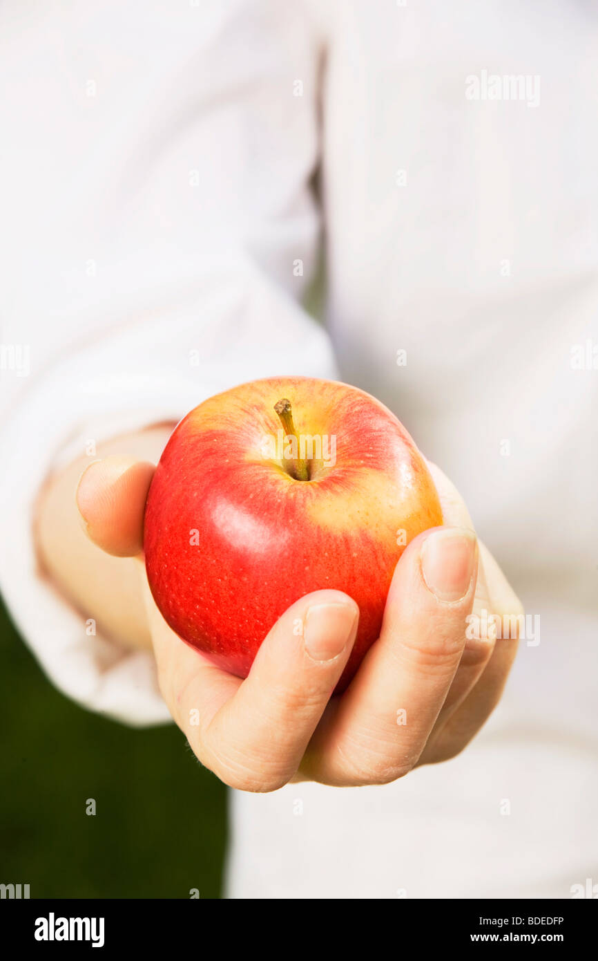 A hand offering a ripe red apple Stock Photo - Alamy