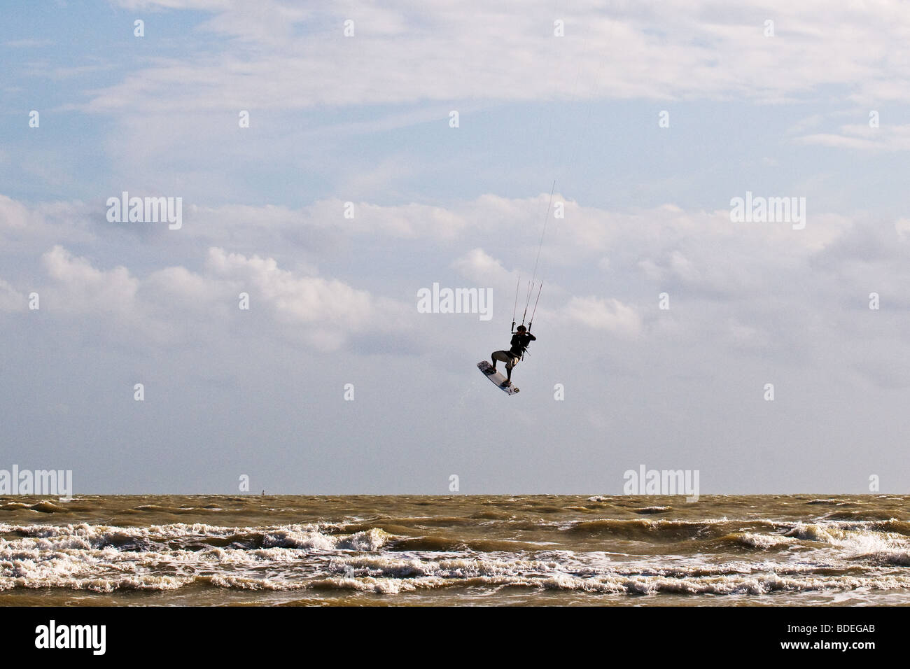 The silhouette of a parasurfer as he performs acrobatic jumps in the ...