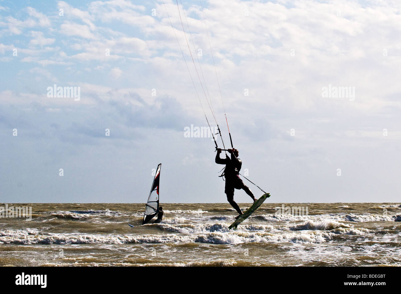 The silhouette of a parasurfer jumping into the air off Camber Sands in ...