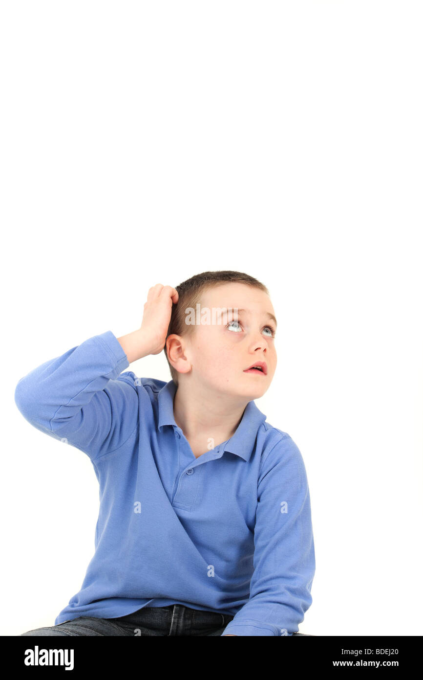 Young boy scratching head against white background Stock Photo - Alamy
