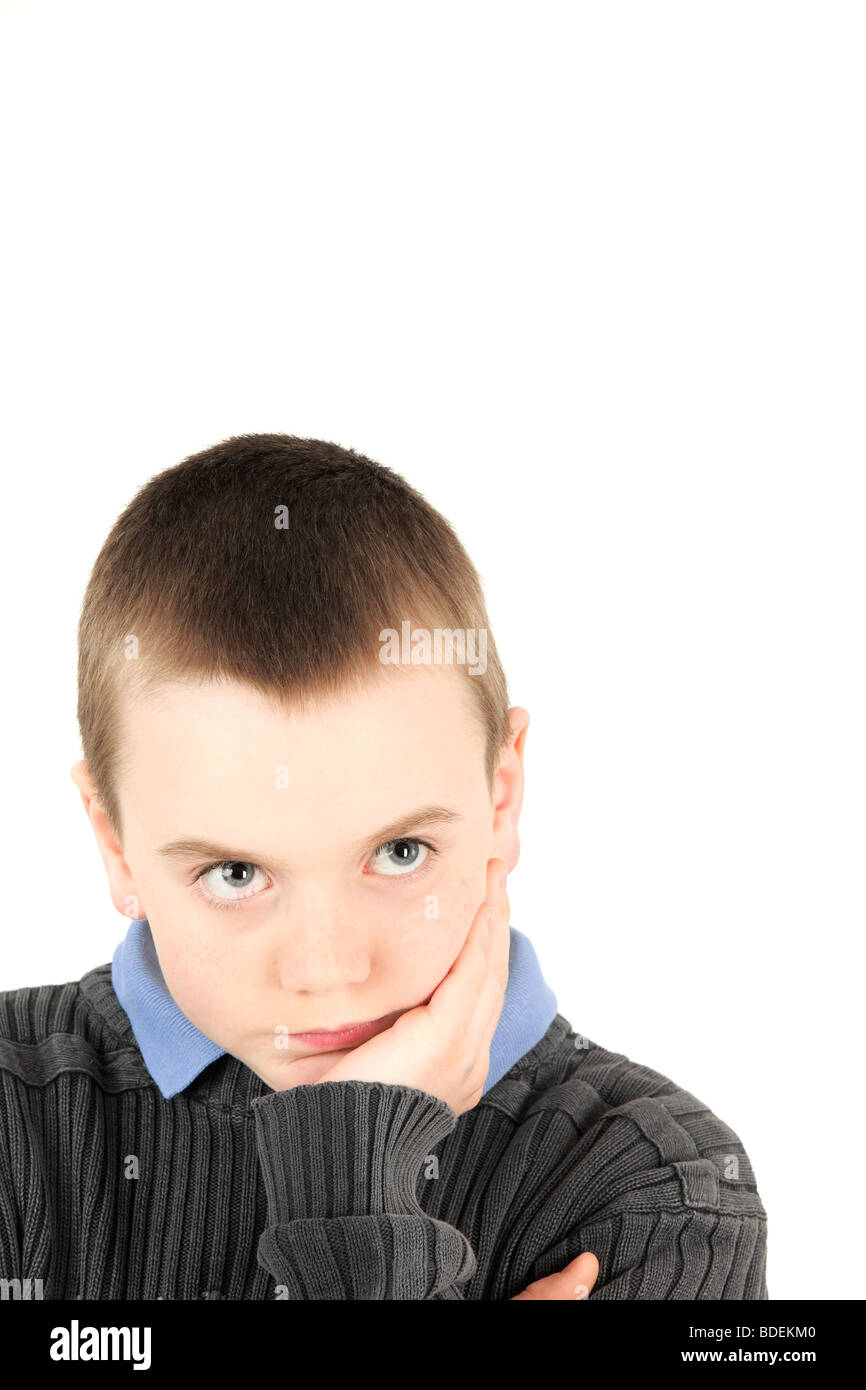 Close-up of young boy resting hand on chin against white background ...