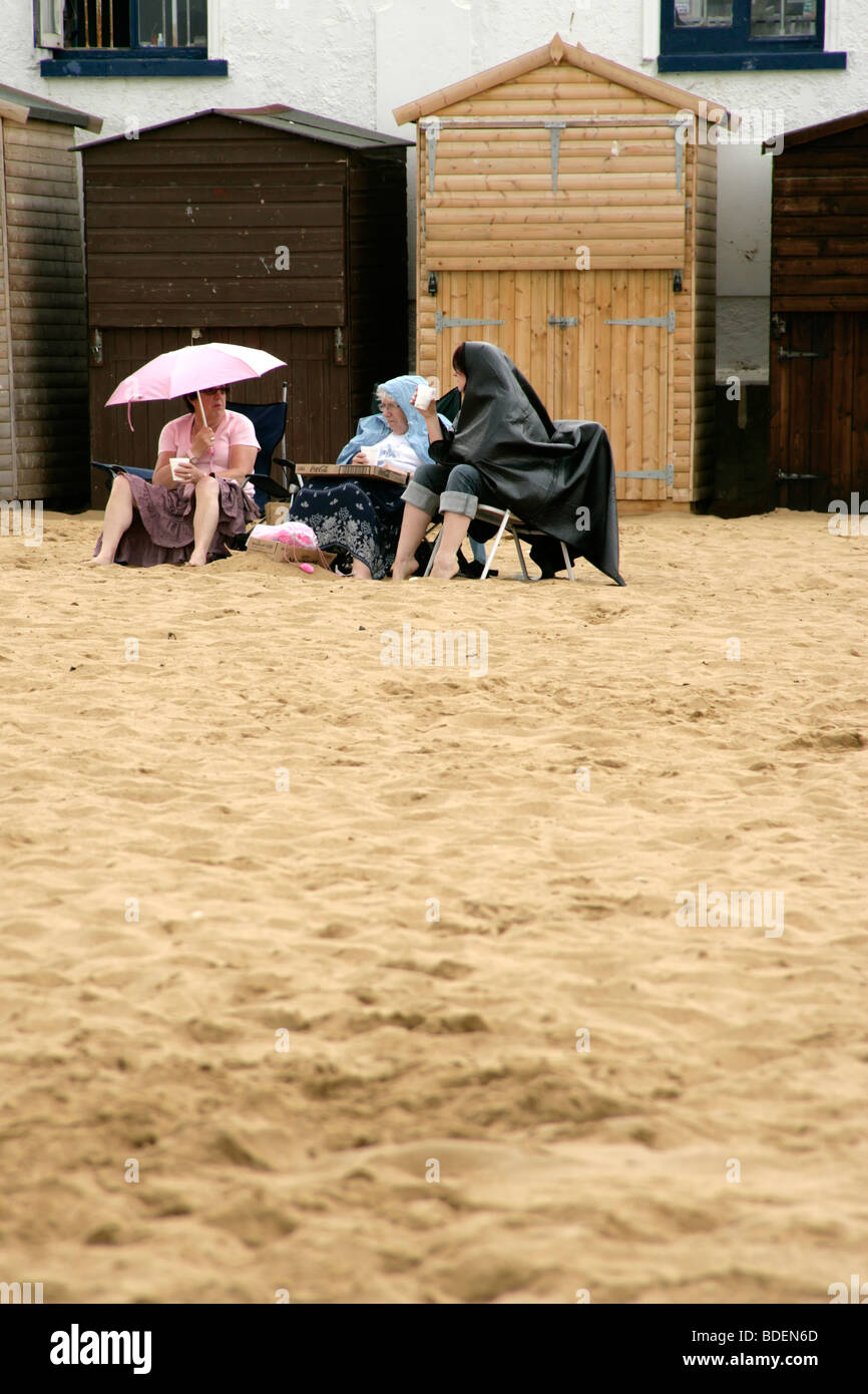 British seaside: holidaymakers sit on the beach in the rain at ...