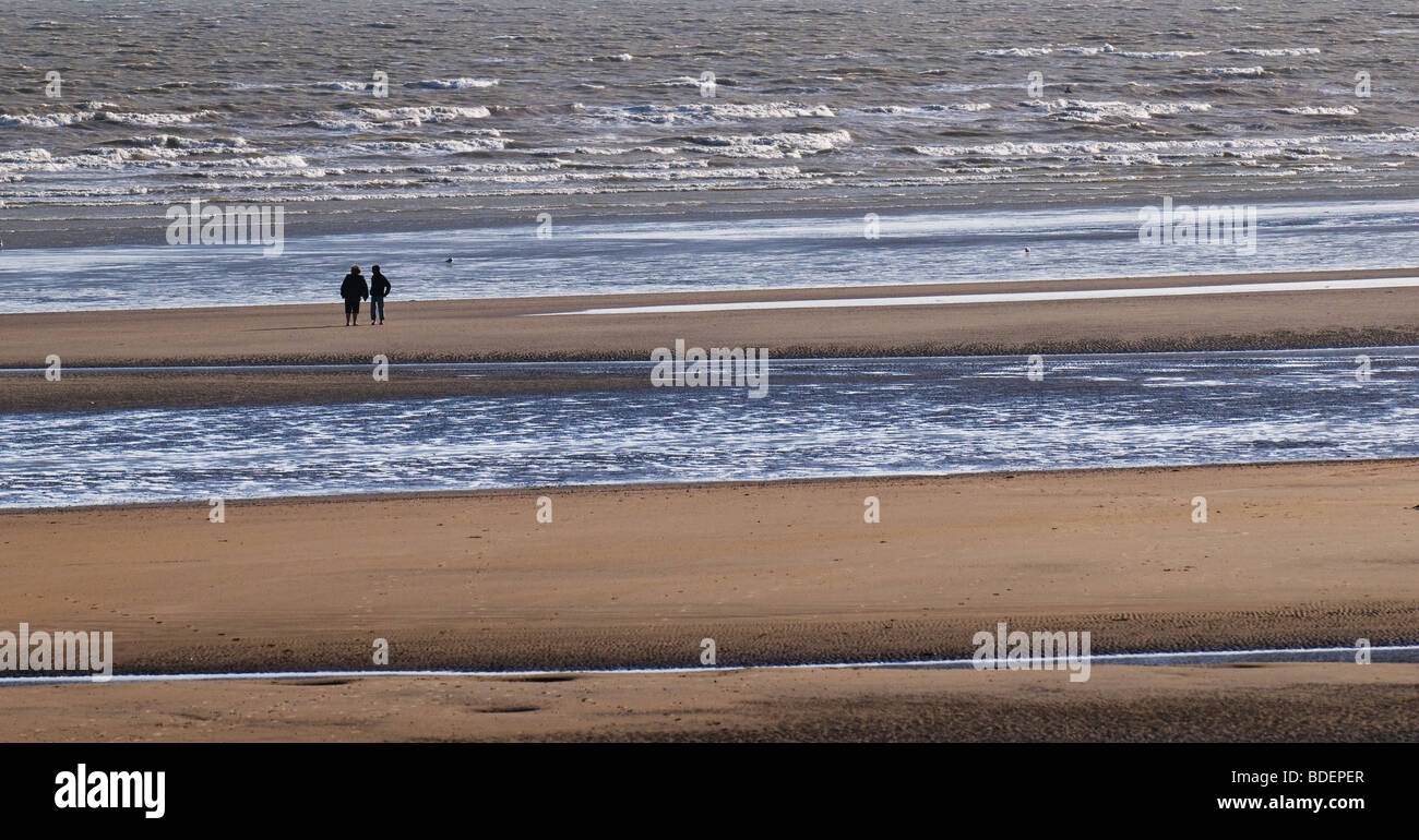 The silhouette of two people walking across the beach at Camber Sands ...
