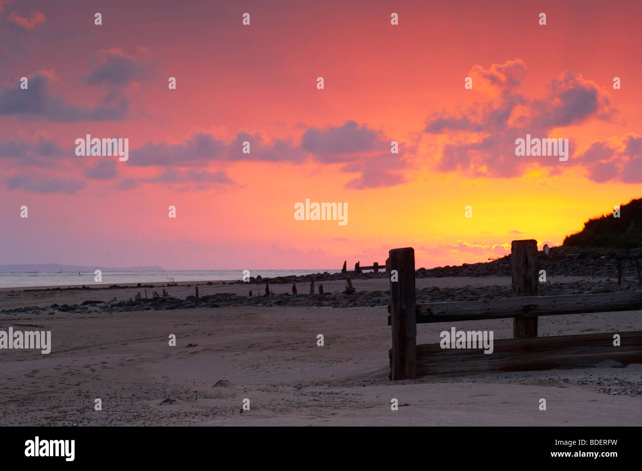 Vivid coloured sunset over timber groynes on the beach at Braunton ...