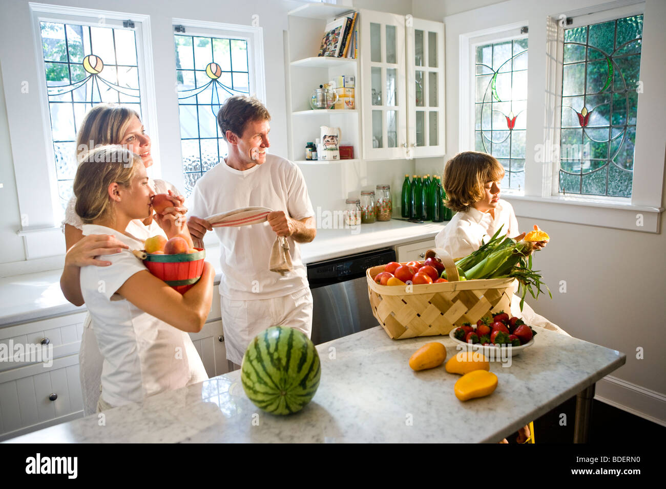Young family in kitchen eating fresh fruits Stock Photo - Alamy