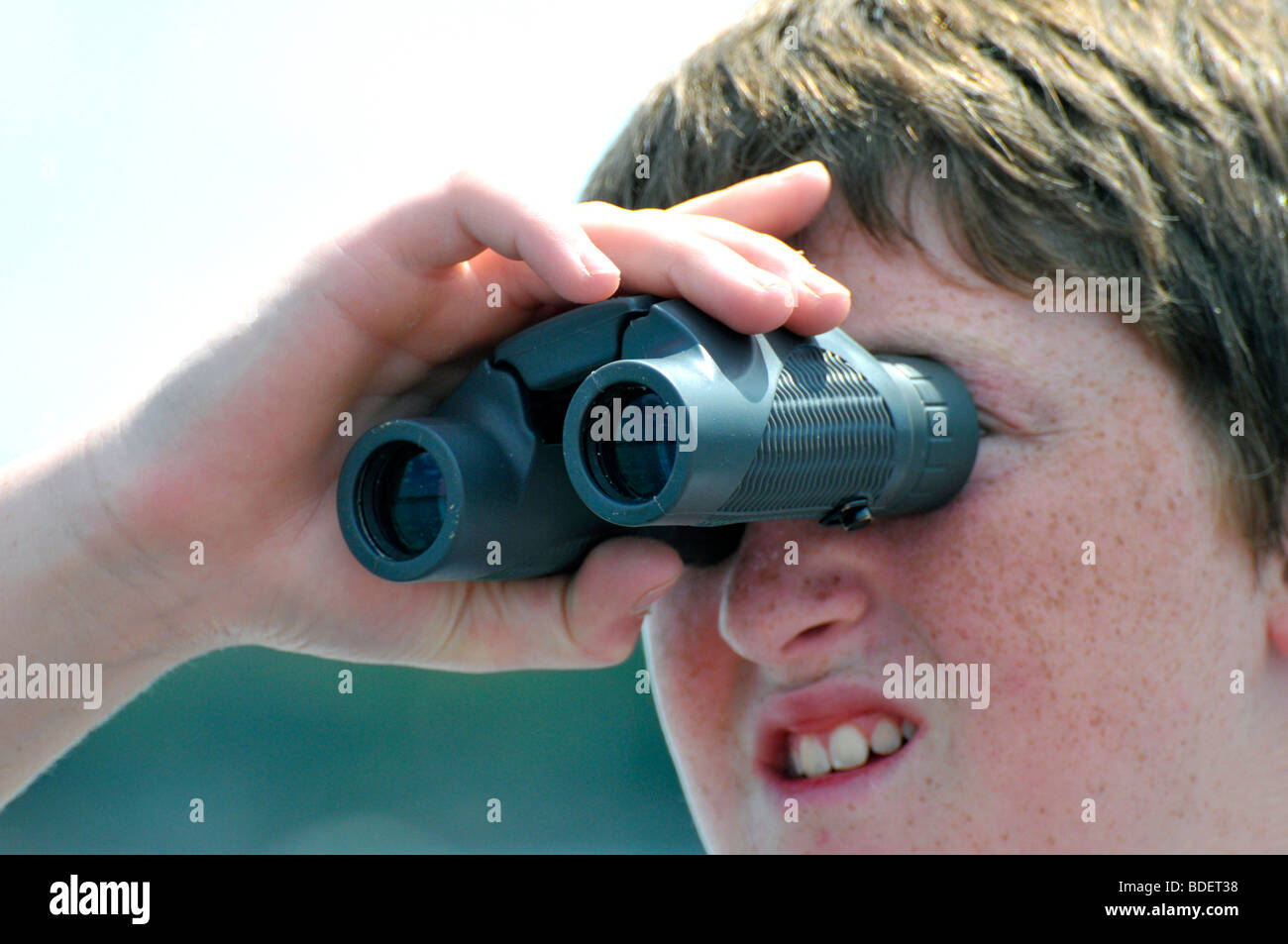 Boy looking through binoculars to see things far away Stock Photo - Alamy