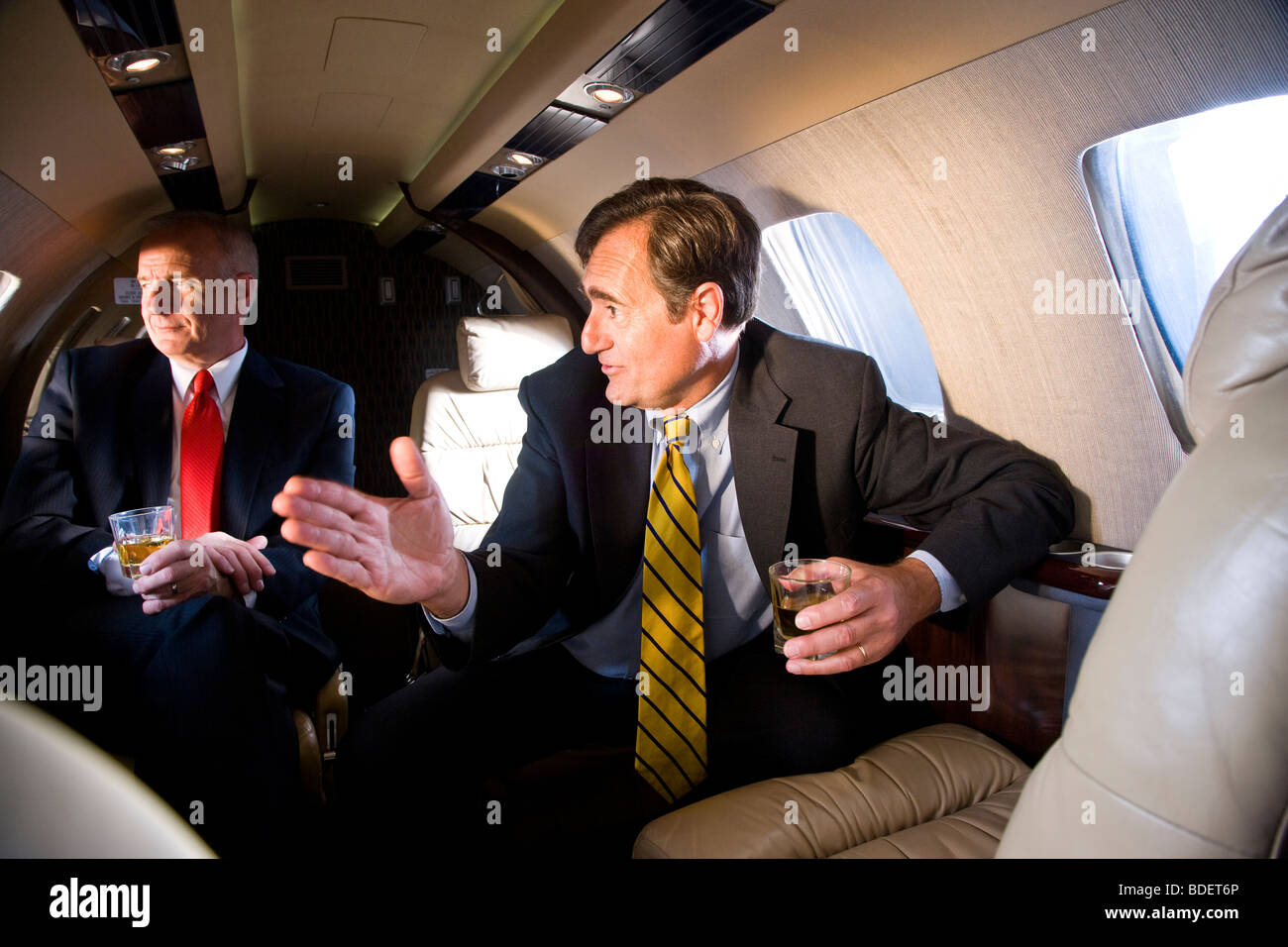 Businessmen with drinks on private jet plane Stock Photo - Alamy