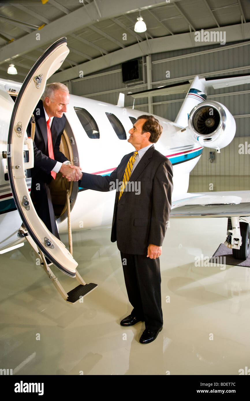 Middle-aged businessmen shaking hands at private jet plane Stock Photo ...