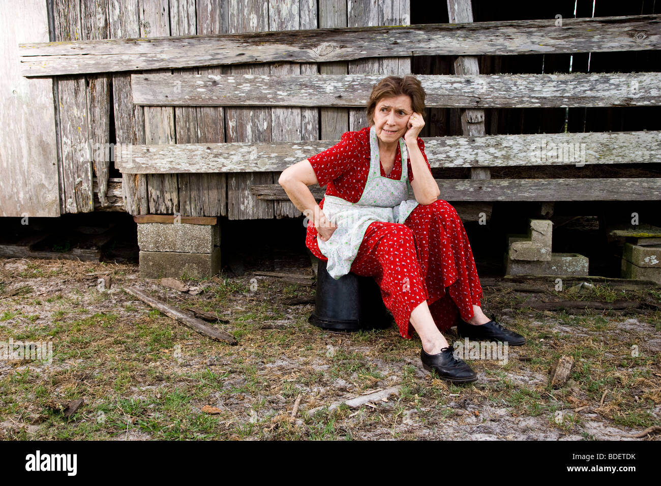 Senior woman sitting on farm near barn worrying Stock Photo - Alamy