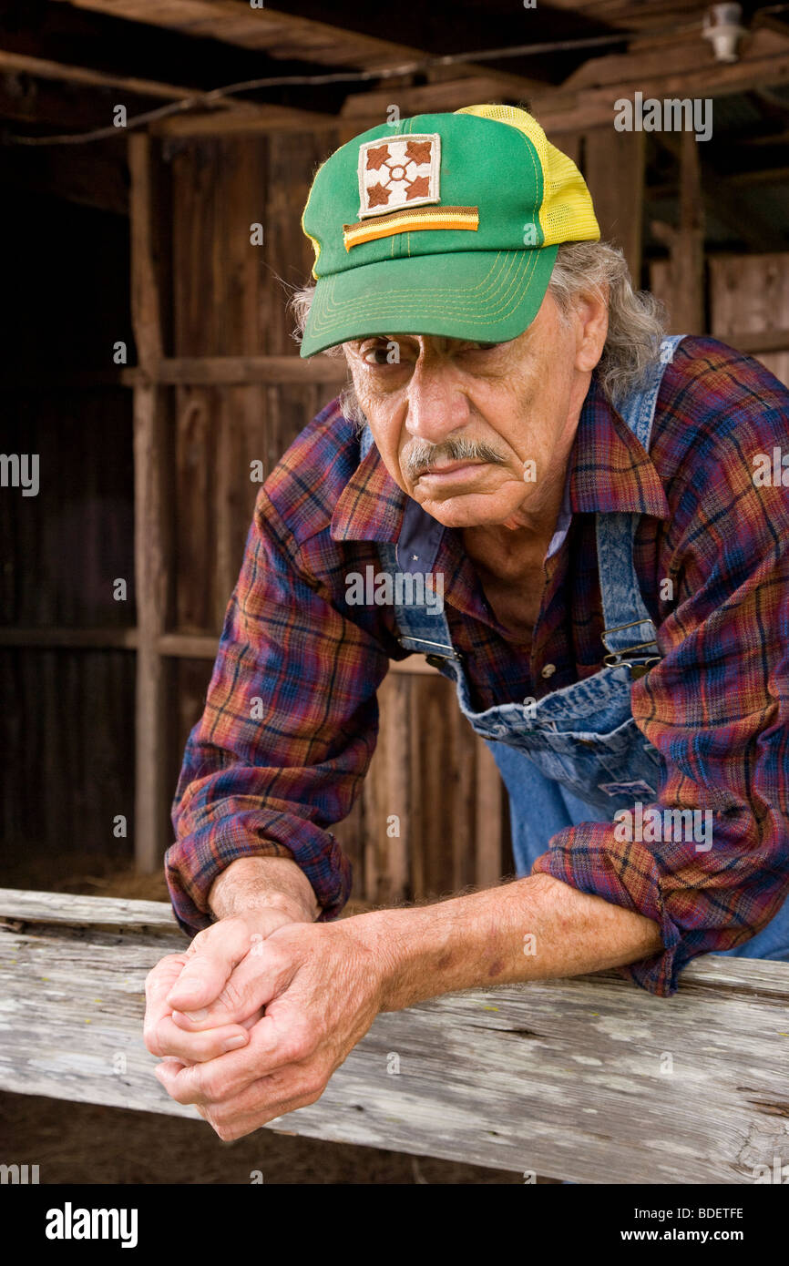 Portrait of senior man wearing green cap leaning on wooden fence Stock ...