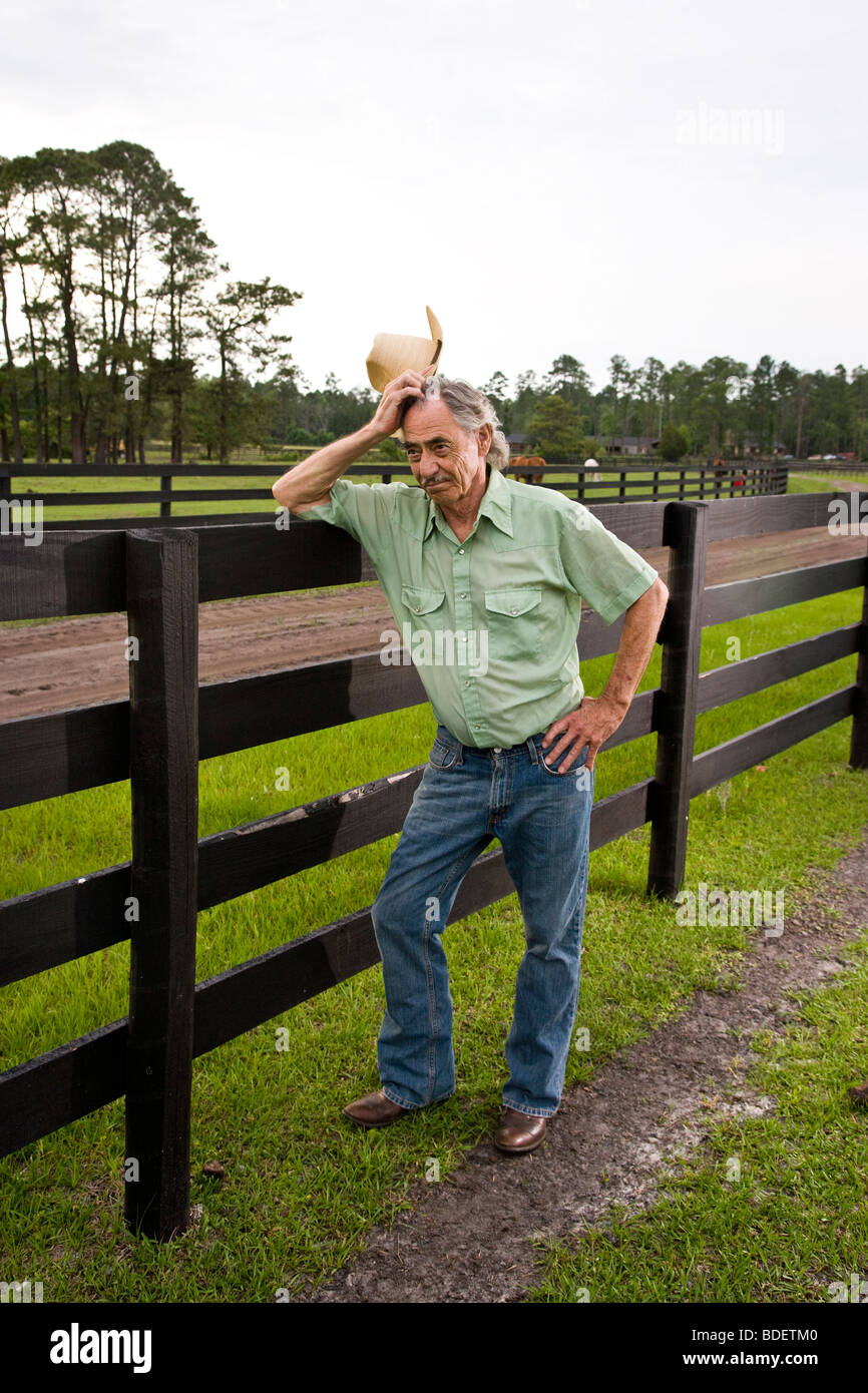 Senior man wearing cowboy hat on ranch leaning on fence Stock Photo - Alamy