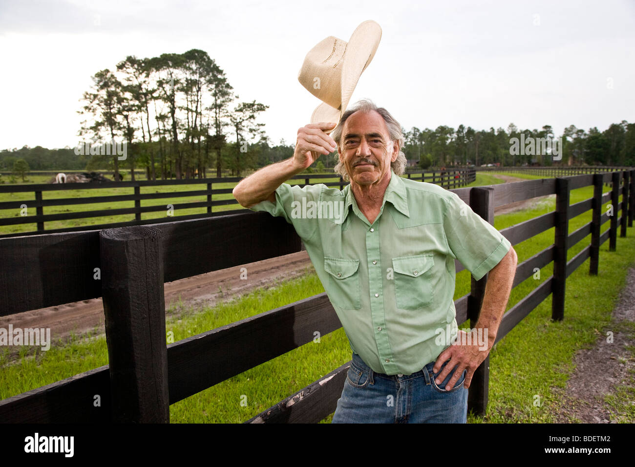 Senior man wearing cowboy hat on ranch leaning on fence Stock Photo - Alamy