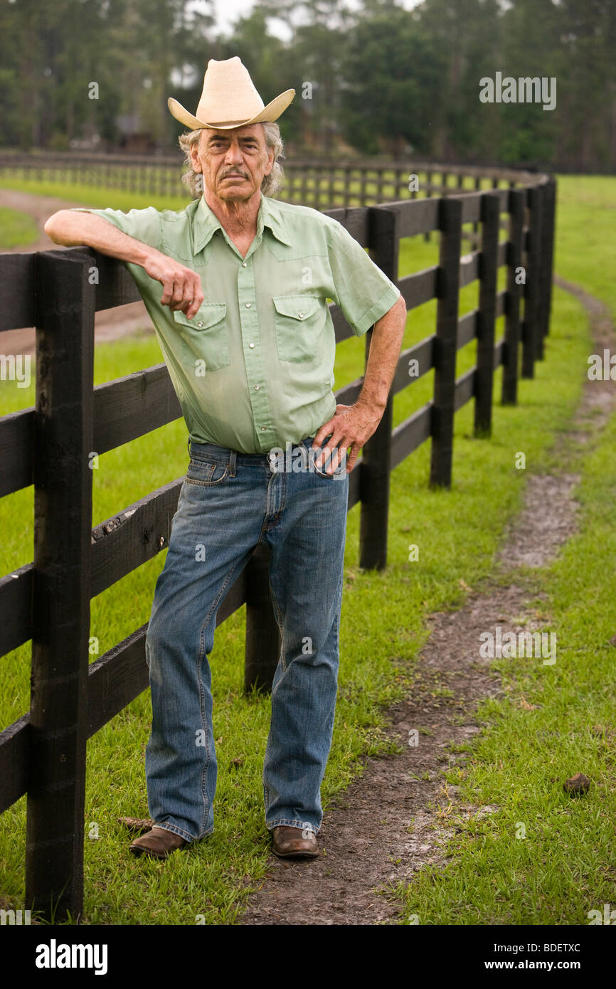 Senior man wearing cowboy hat on ranch leaning on fence Stock Photo - Alamy