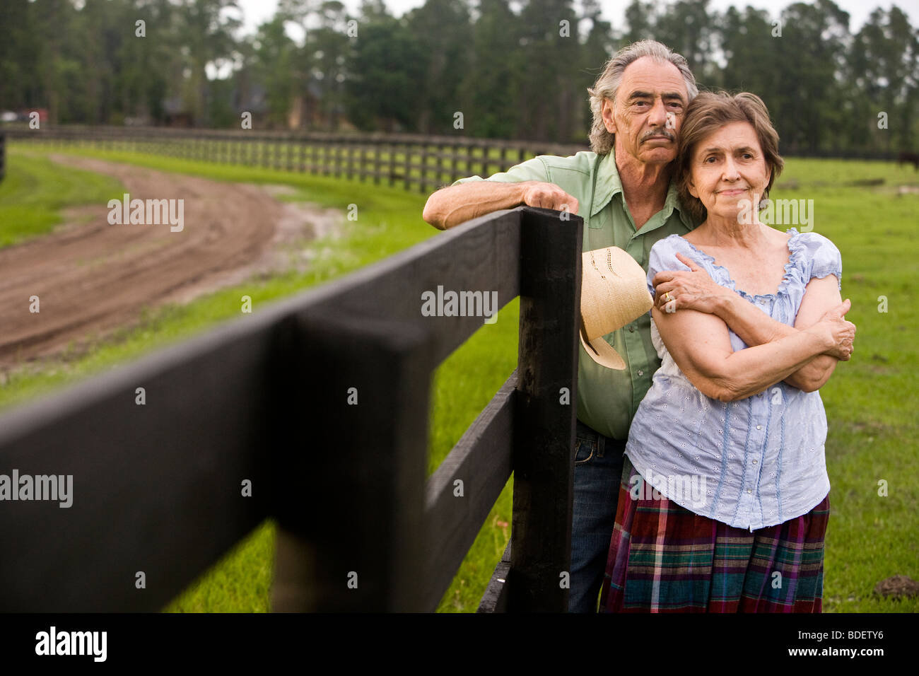 Senior couple standing on ranch near fence Stock Photo - Alamy