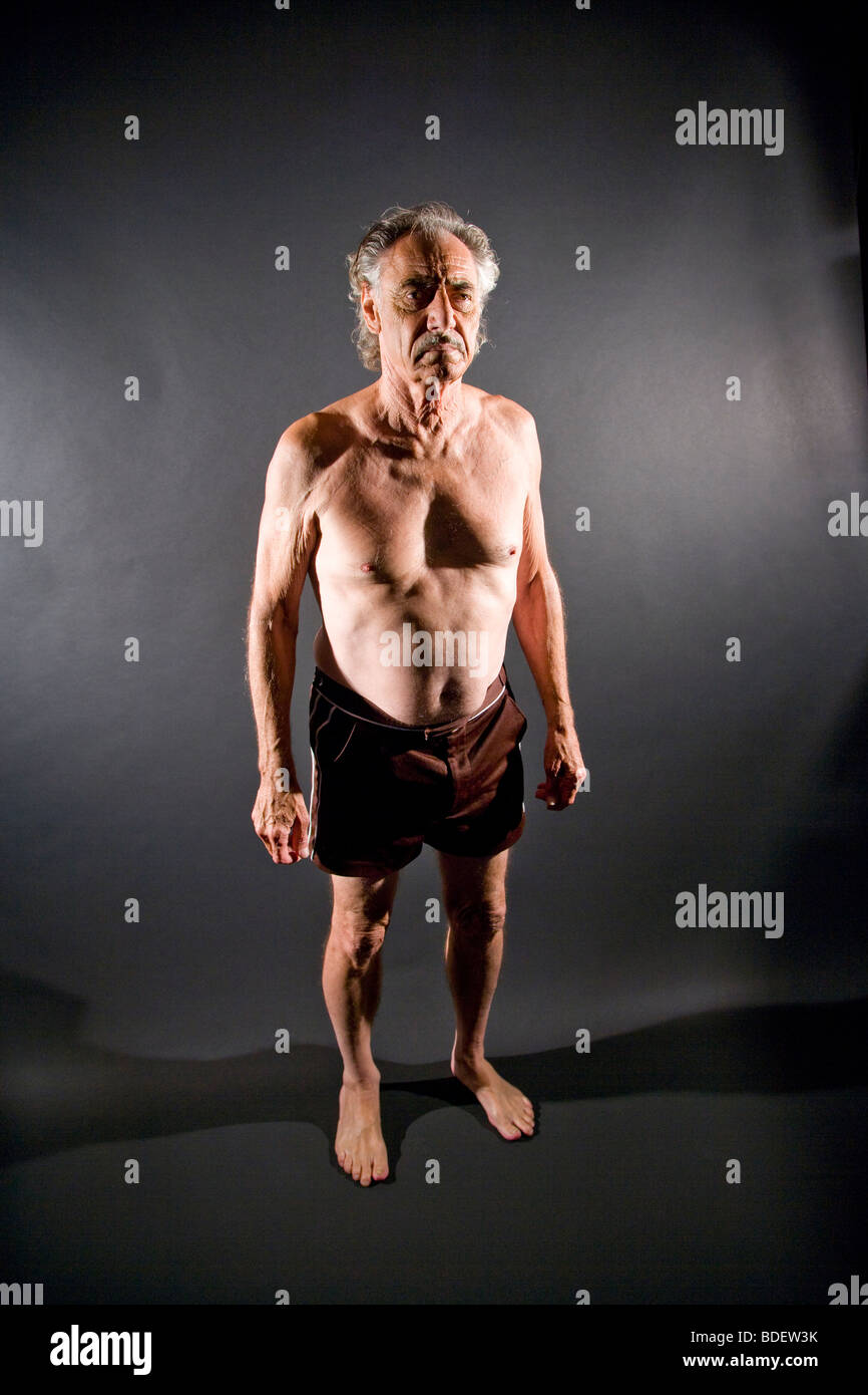 Serious senior man in boxer shorts standing against gray background ...