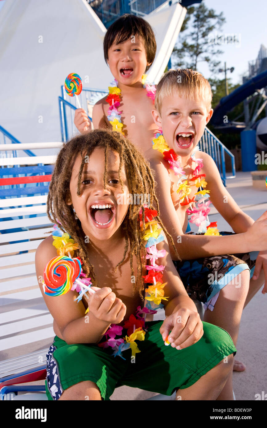 Boys with lollipops and flower leis at water park in summer Stock Photo ...