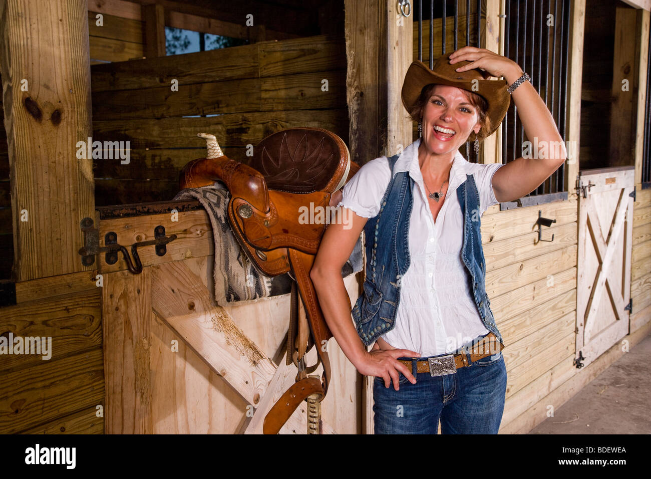 Attractive woman holding saddle in stable Stock Photo - Alamy