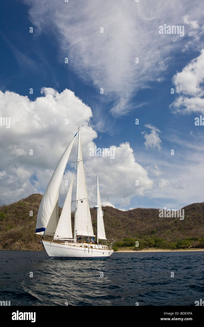 Ketch rig sailboat cruising along the shoreline in the Papagayo Bay ...
