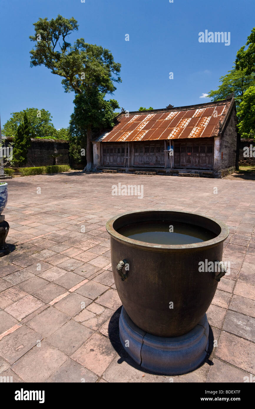 A large metal urn stands in a paved courtyard in the palace of Hue ...