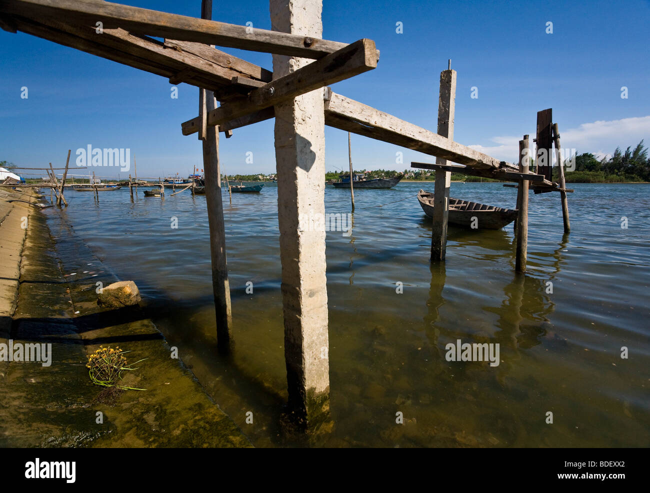 A simple jetty made from a few planks and bamboo juts into the river at ...