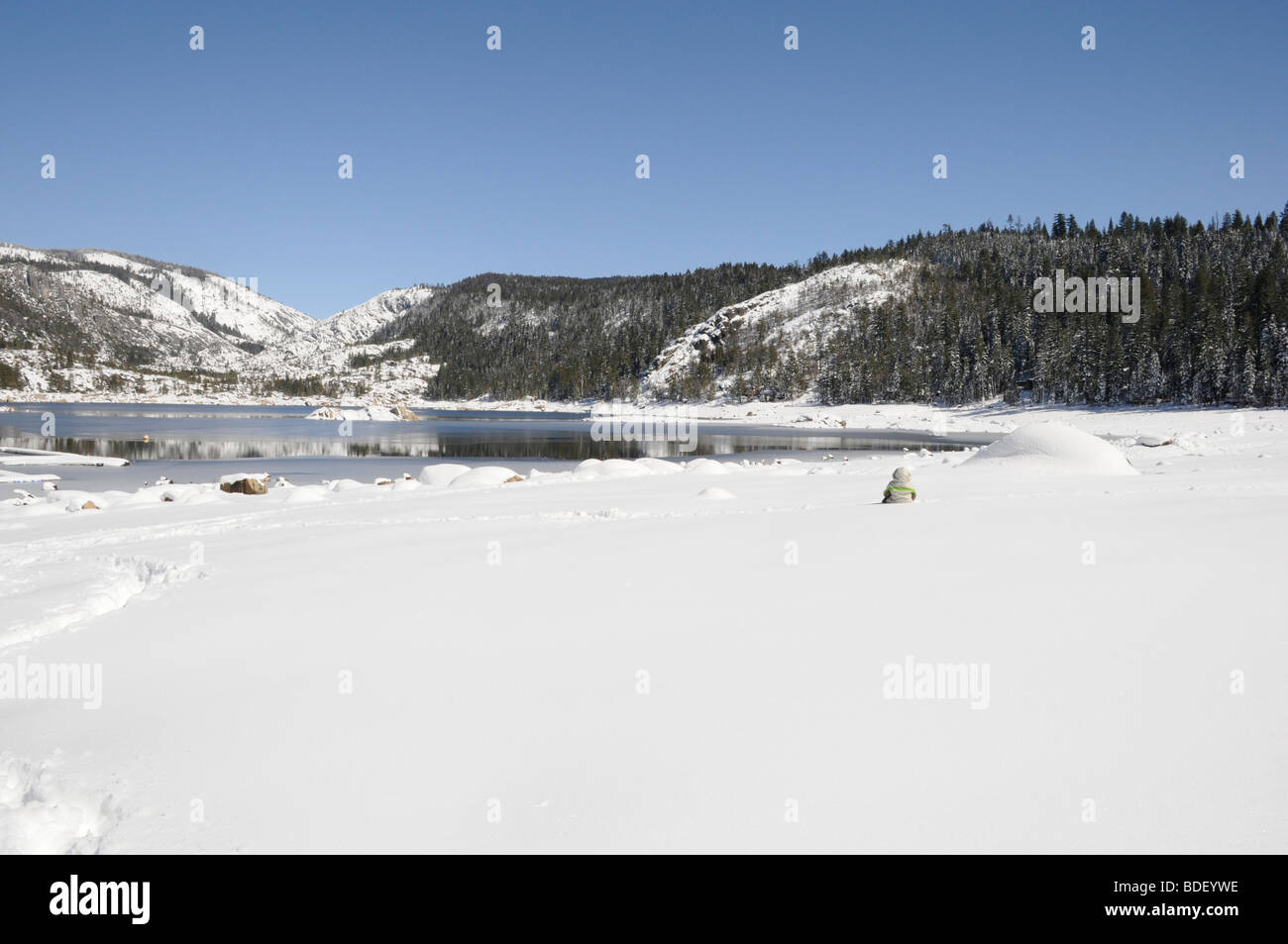 Snowy place of fun, families frolic and sledge near icy lake in soft ...