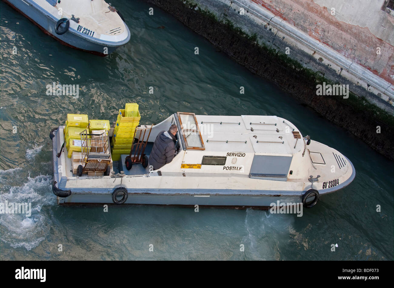 postal service boat delivering parcel and mail on canal in VeniceI taly ...