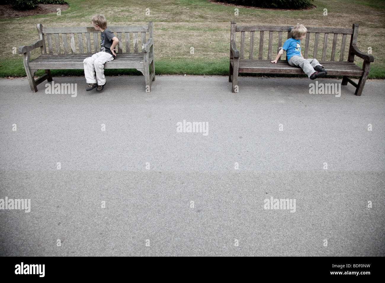 Two young boys sitting on separate park benches Stock Photo - Alamy