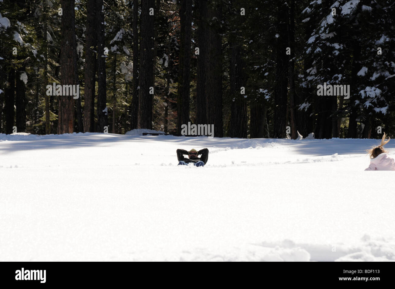 Snowy place of fun, man lies in snow smiling at camera in soft, waist ...