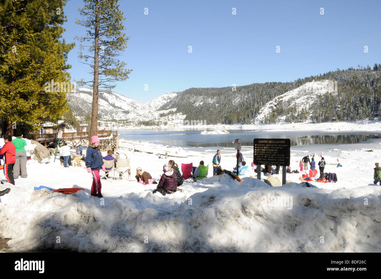Snowy place of fun, families frolic and sledge near icy lake in soft ...