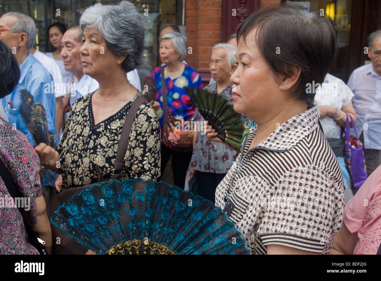 Senior citizens in Chinatown in New York wave fans to cool themselves ...