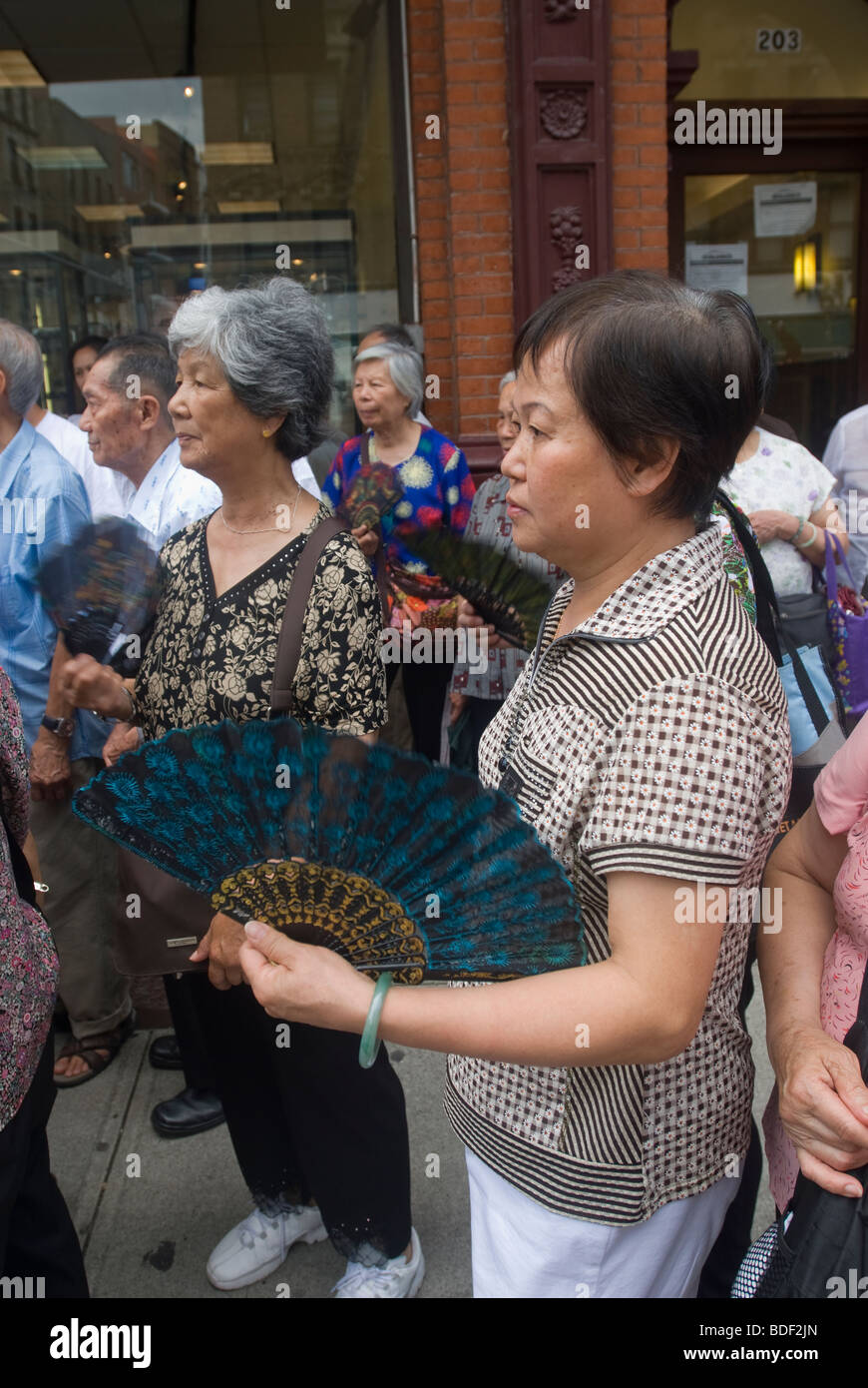 Senior citizens in Chinatown in New York wave fans to cool themselves ...
